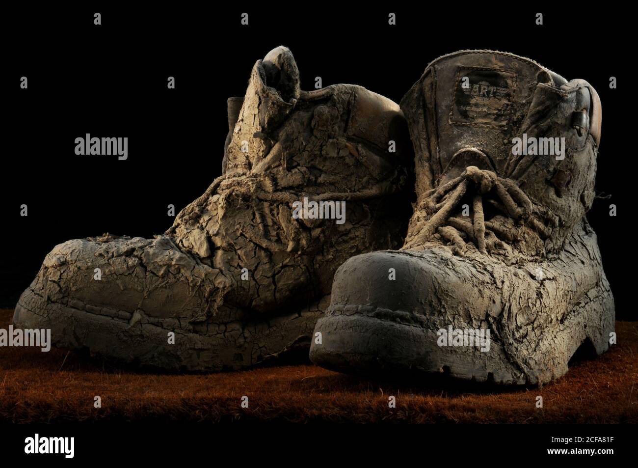 Pair of old worn walking boots covered in dried on thick mud with ...
