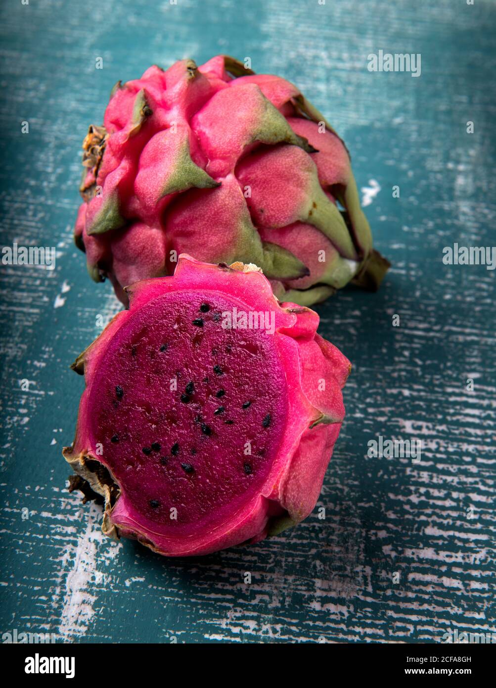 High angle of tropical pitaya fruits with pink pulp placed on wooden ...