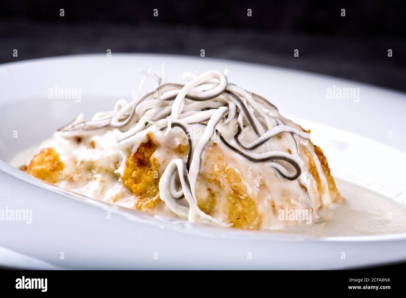 Delicious roasted hake and boiled baby eels with white sauce in ceramic ...