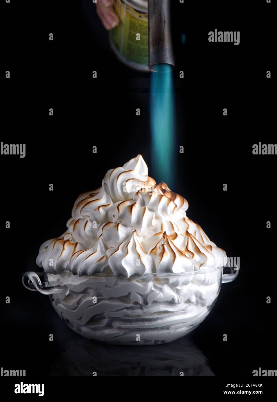 Process of browning fresh meringue pile over baked vanilla souffle in ...