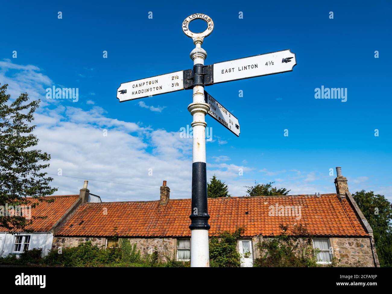 Old fashioned signpost with hand pointing to villages in mile distances ...