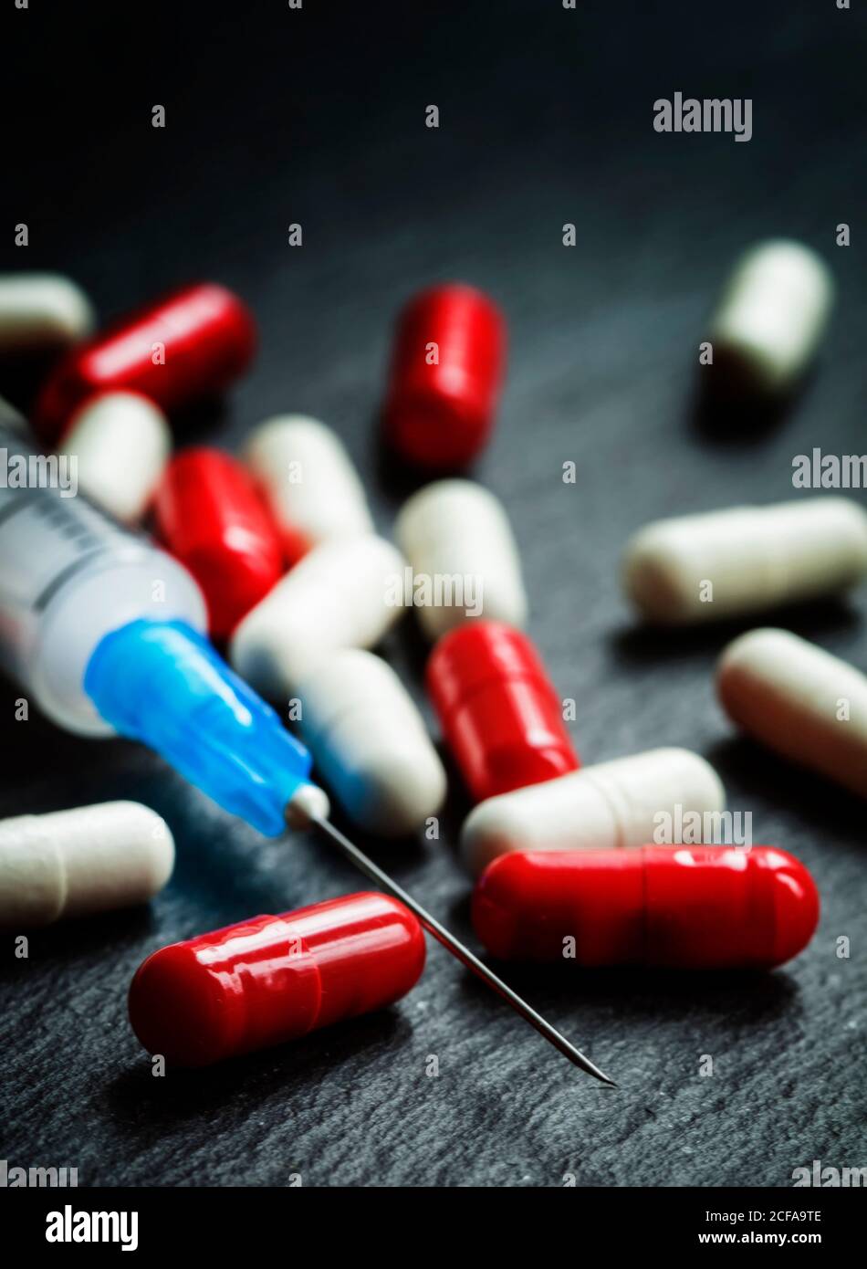 Red and white tablets in capsules, syringe for injection, dark ...