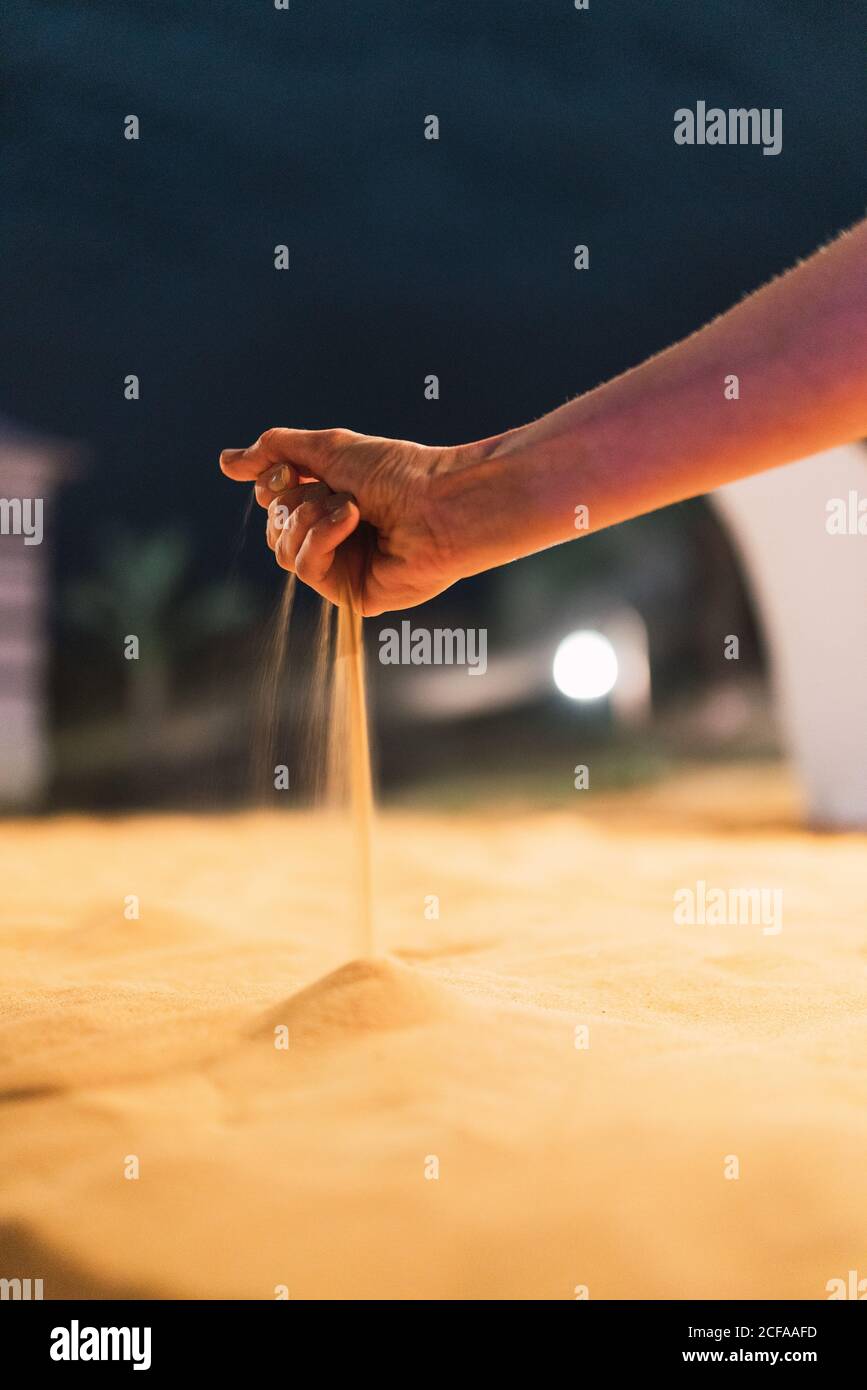 Crop hand spilling dry sand Stock Photo - Alamy