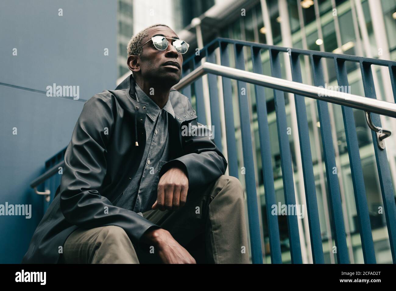 Stylish black man sitting on haunches on street Stock Photo - Alamy