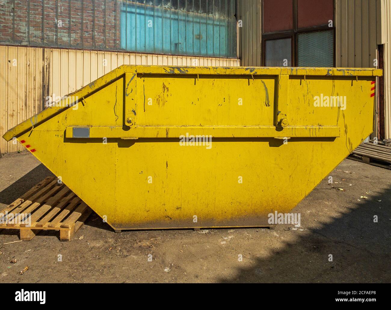 Yellow Skip Container in Front of Building Stock Photo - Alamy
