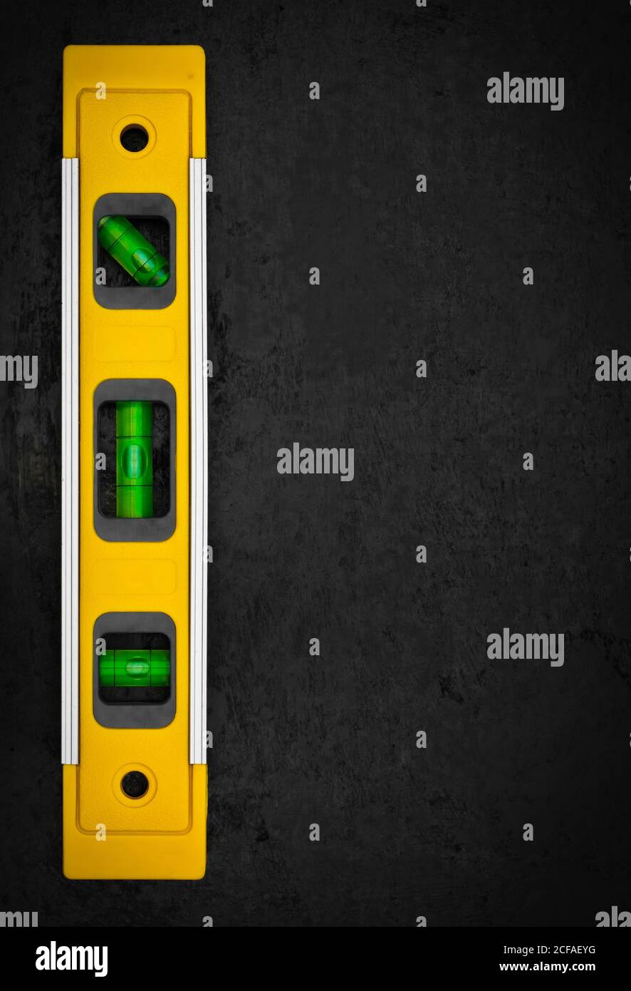 Yellow bubble level on a textured black metallic background with space ...