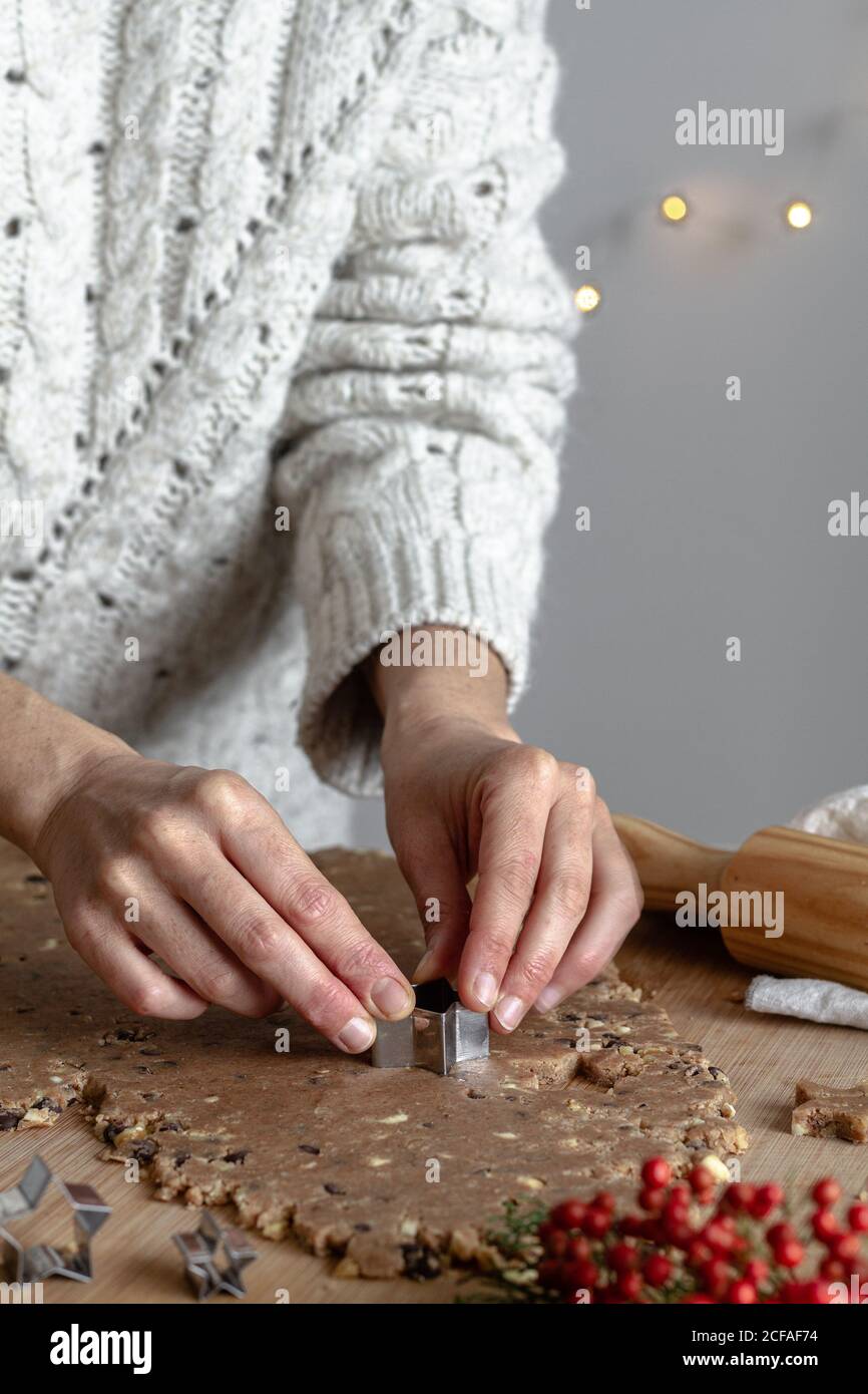 Crop hands of faceless Woman making gingerbread cookies with tin form ...