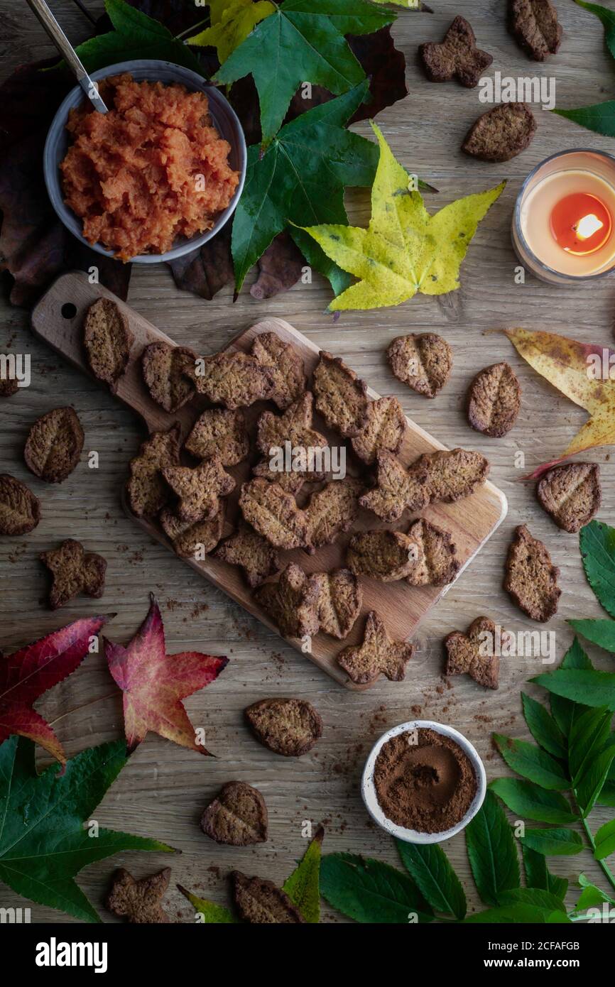 Top view of tasty biscuits and autumn leaves placed on wooden table ...