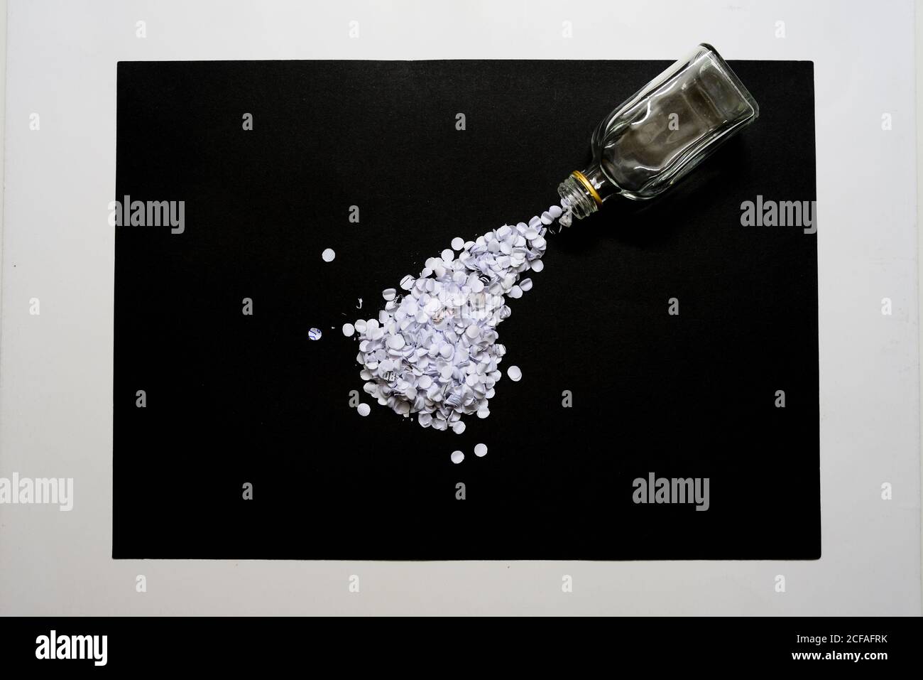 High angle shot of a glass container with spilled out circle paper ...