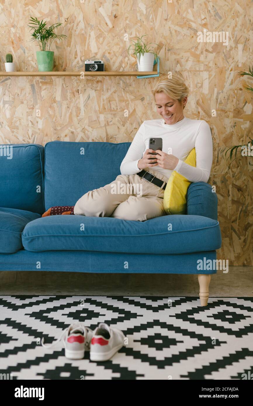 Side view of casual cheerful Woman texting on smartphone while having ...