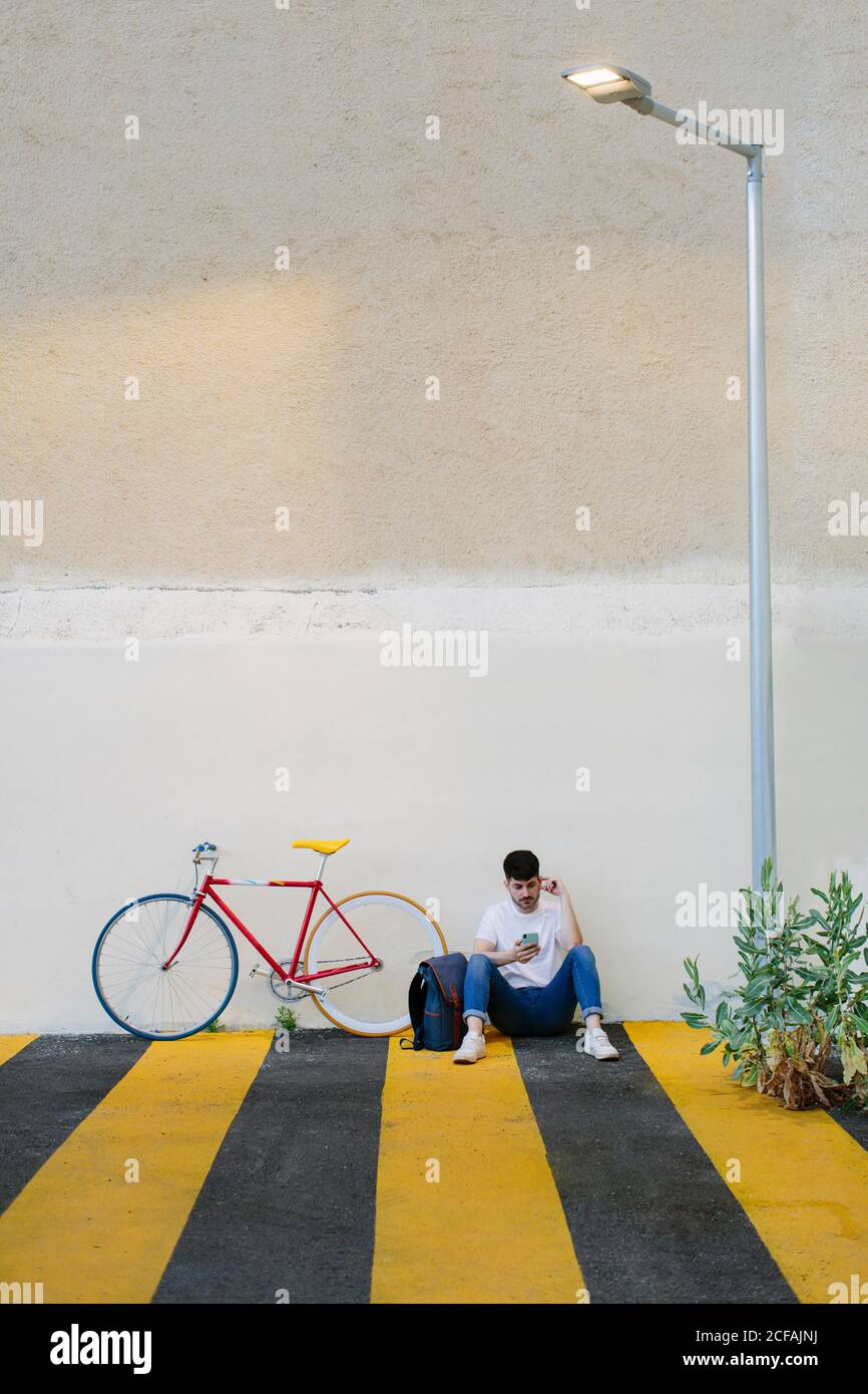 Front view of a man sitting on the floor with a fixie bike Stock Photo ...