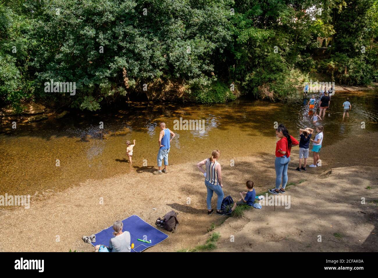 Families relaxing and paddling in the River Roding Wanstead Park in the ...