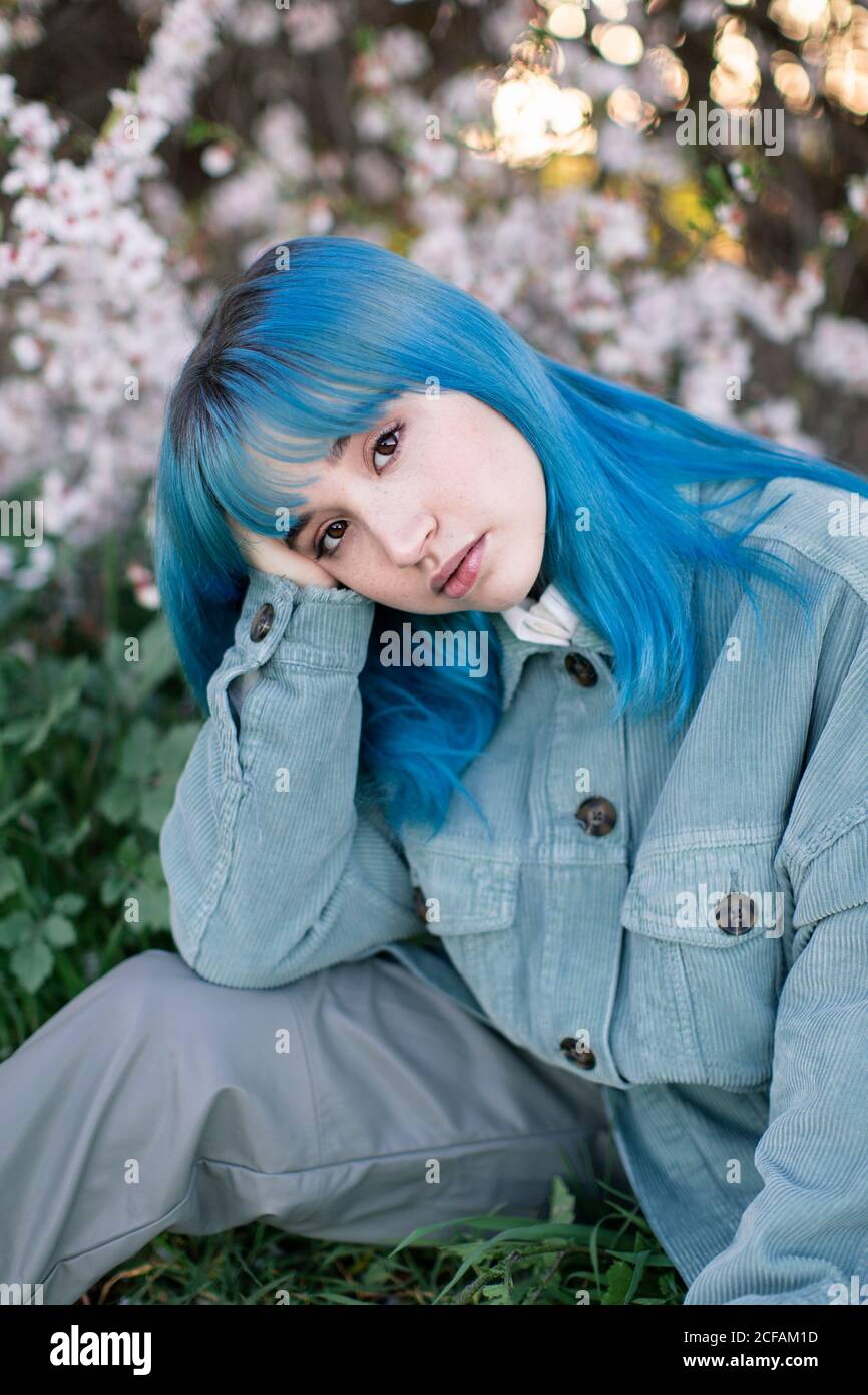 Sad millennial female model with blue hair in stylish outfit looking at ...