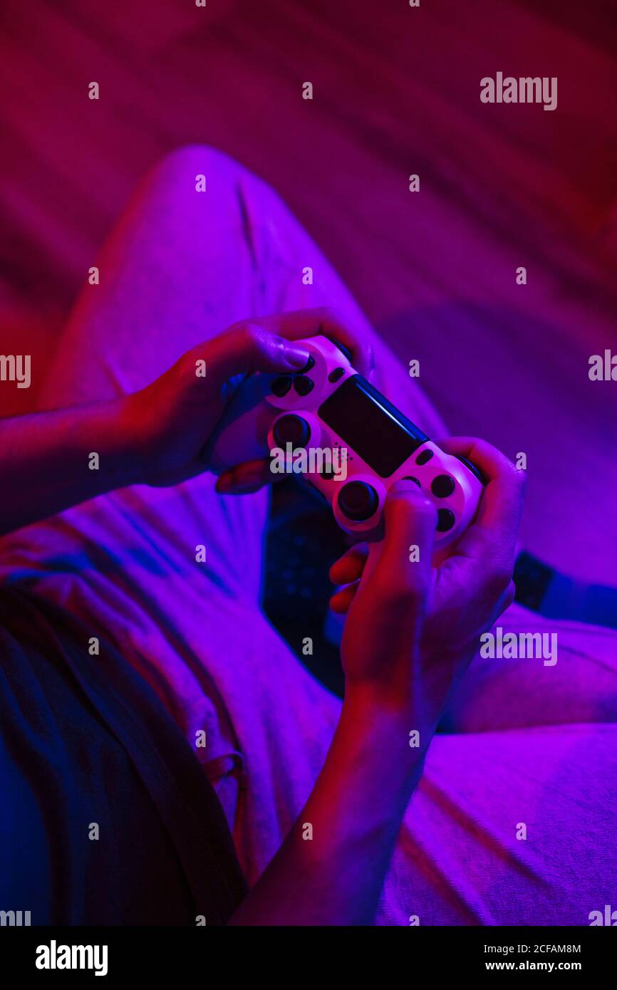 Close-up view of a boy's hands playing video games sitting on the floor ...