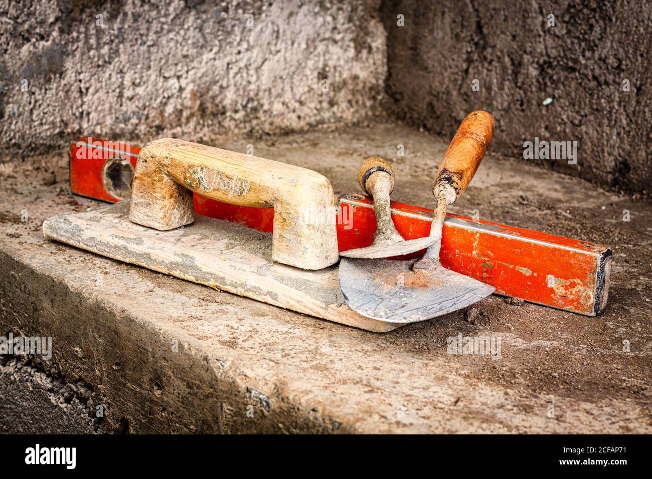 Trowels and other masonry tools on an unfinished concrete wall ...