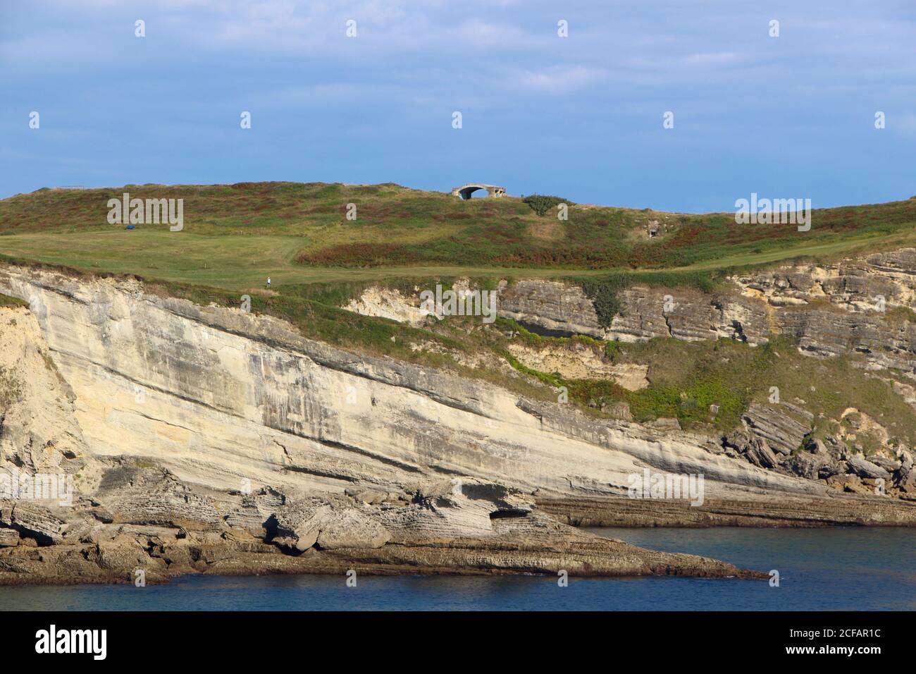 Rocky coastal landscape with a ruined arched structure on top of cliffs ...