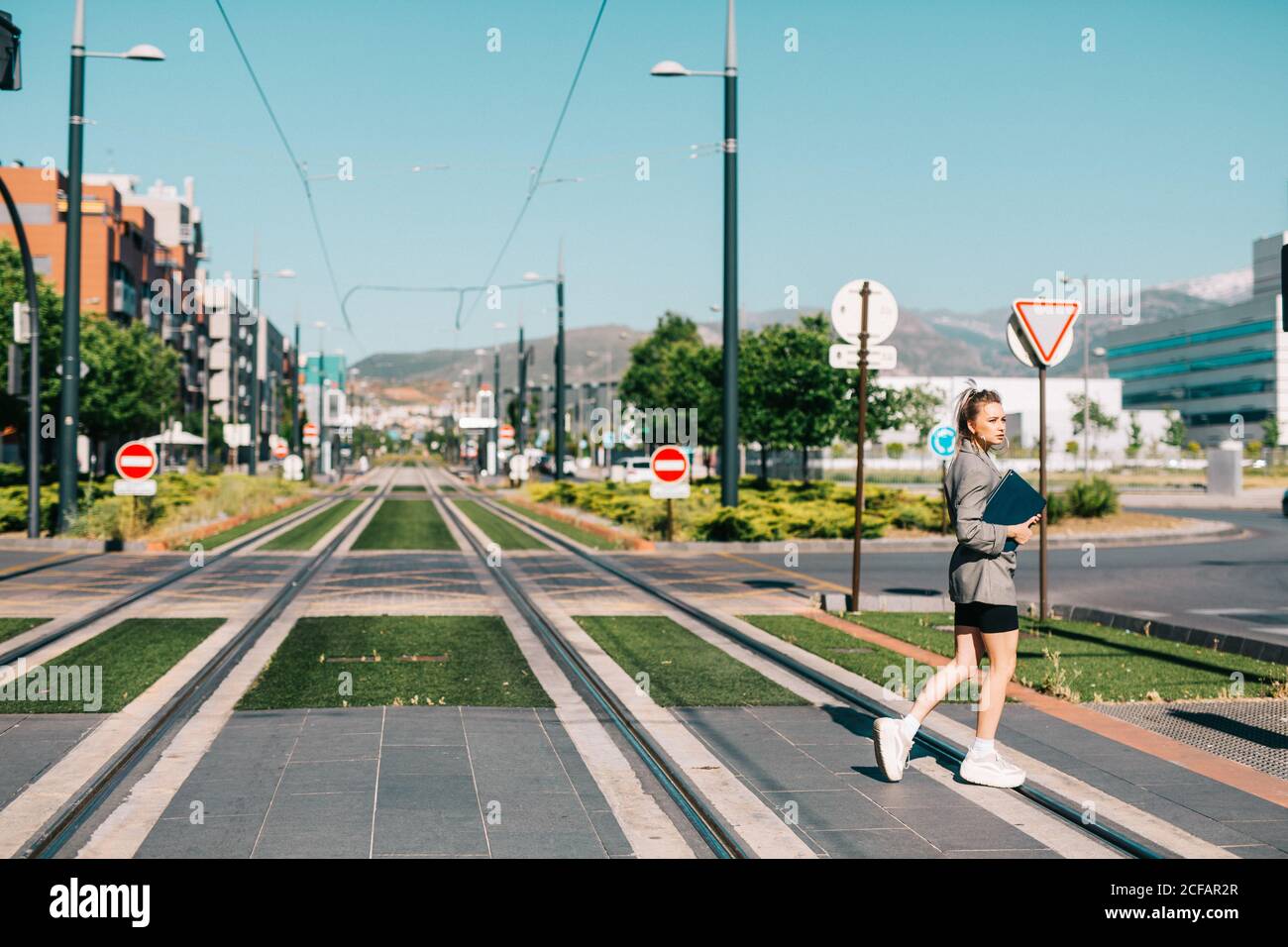 Side view of trendy Woman in stylish suit with black notebook fast ...