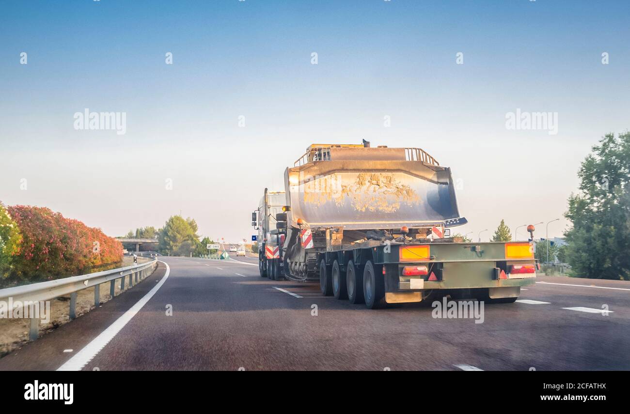 Oversize load truck transporting a huge excavator machine. View from ...