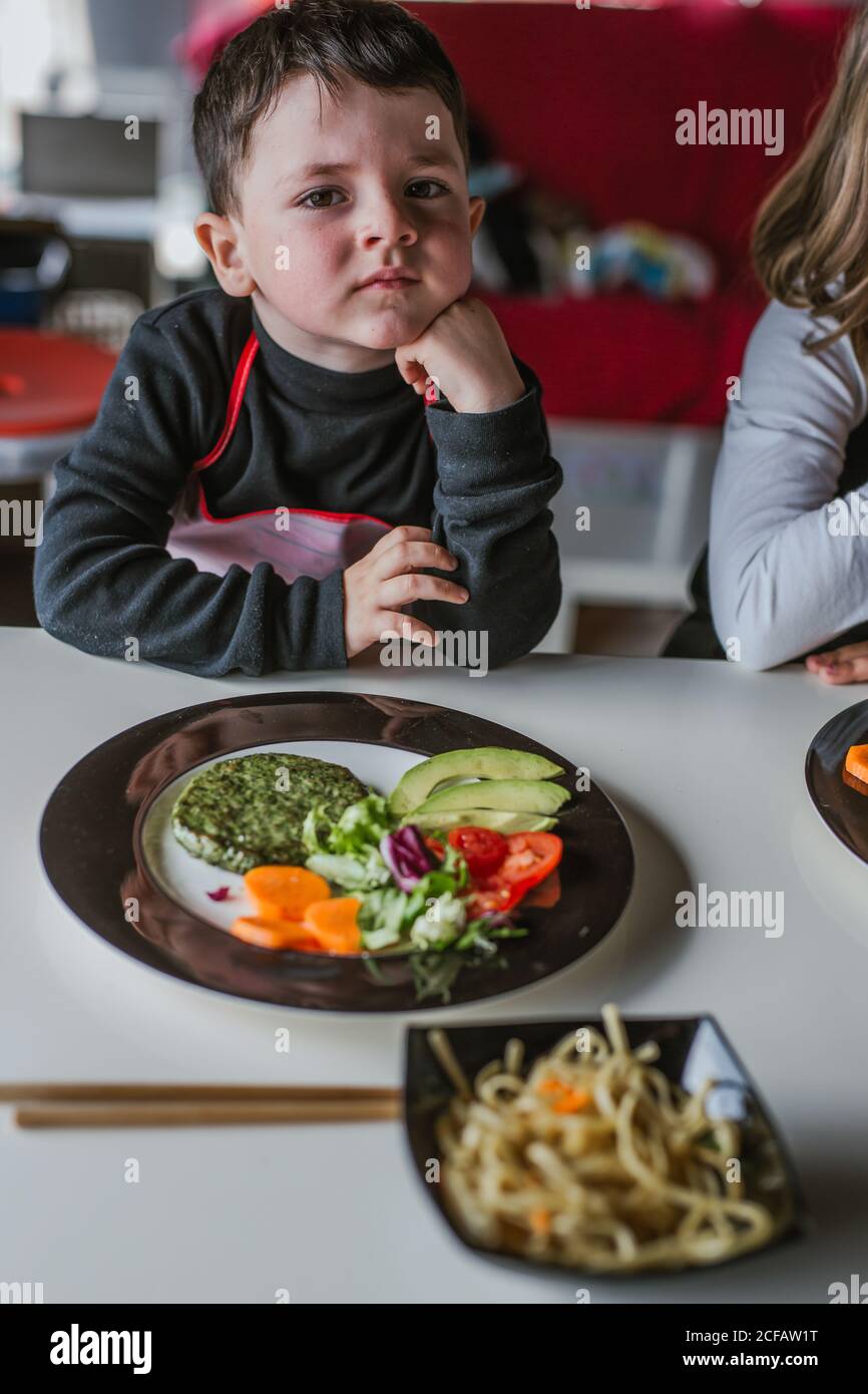 boy waiting to eat tasty noodles with vegetarian cutlets and vegetables ...