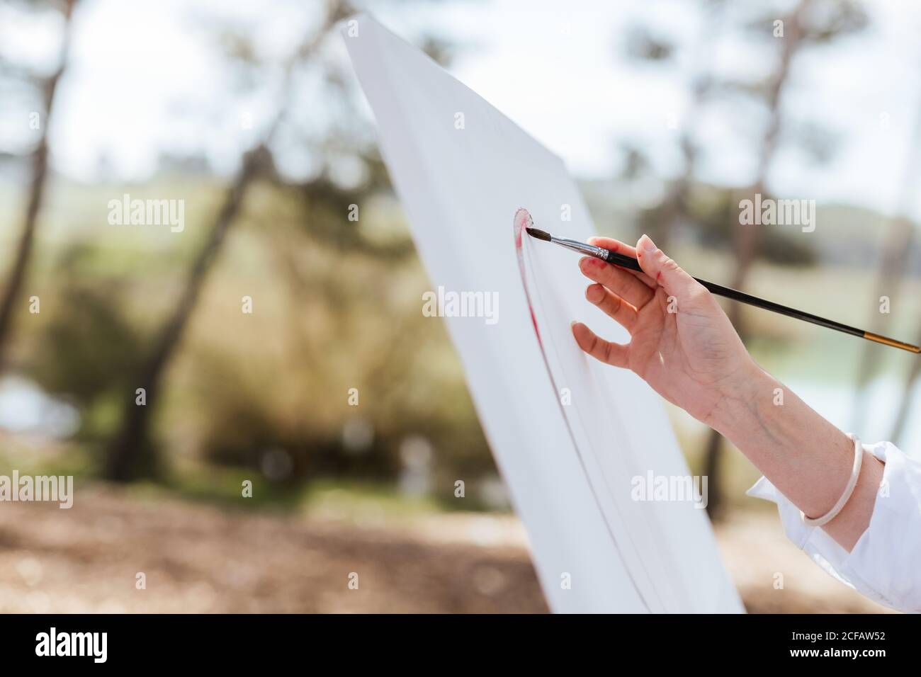Hand of anonymous Woman using paintbrush to draw picture on canvas on ...
