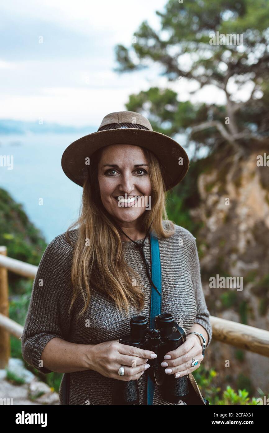 Adult Woman observing view with binocular while standing at fence on ...