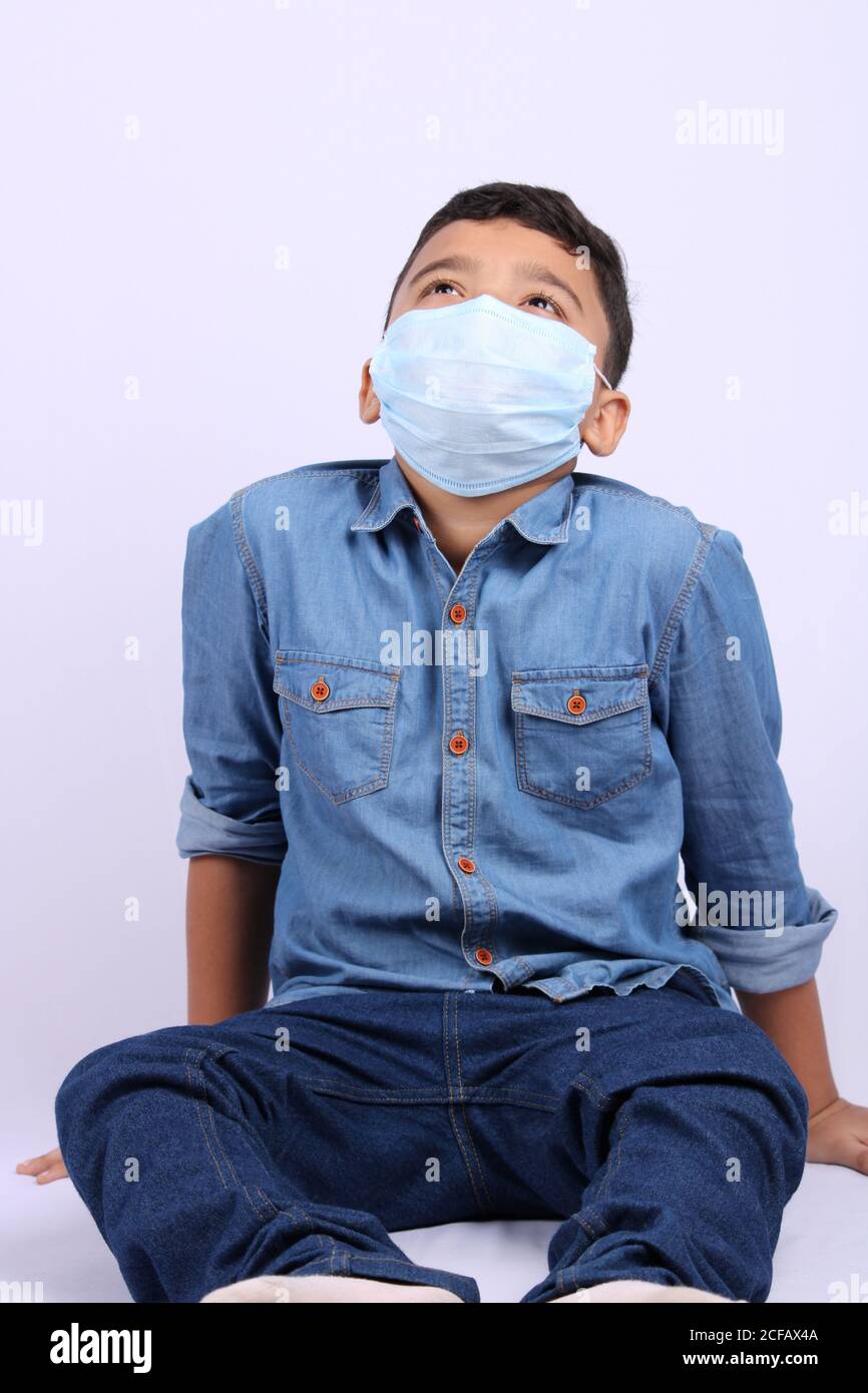 Cute Indian boy with mask relaxing over white background Stock Photo ...
