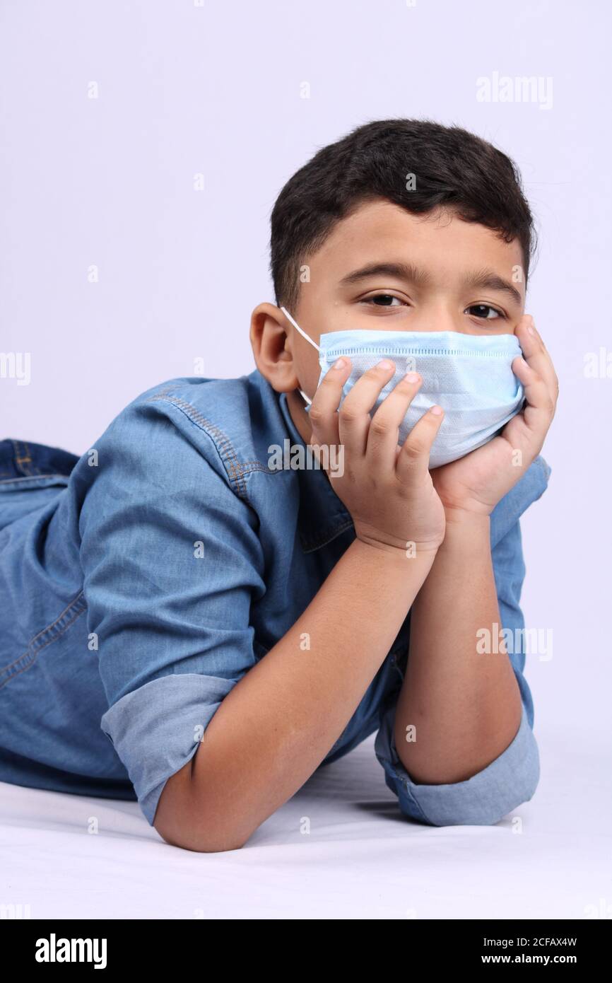 Cute Indian boy with mask relaxing over white background Stock Photo ...