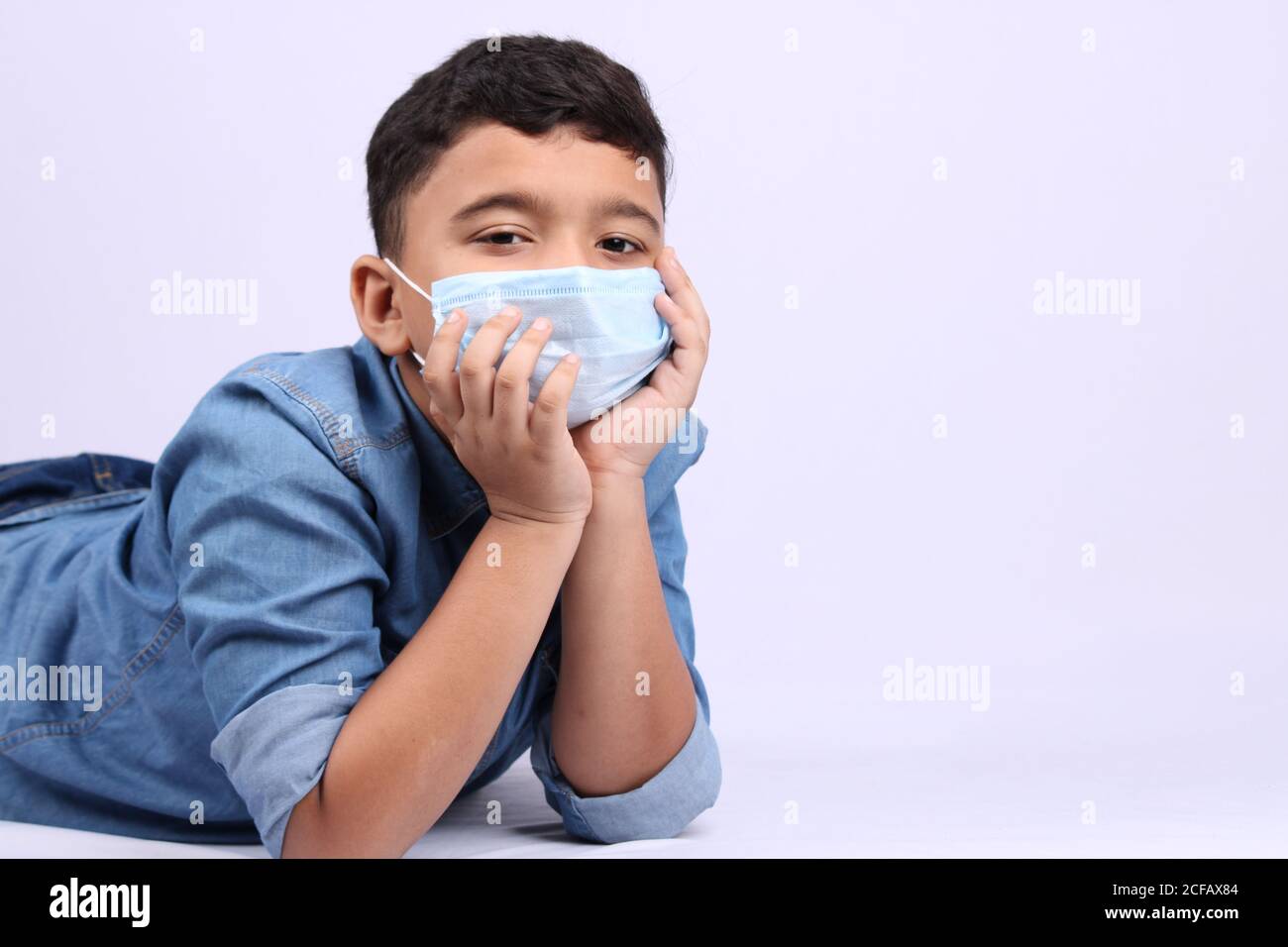 Cute Indian boy with mask relaxing over white background Stock Photo ...