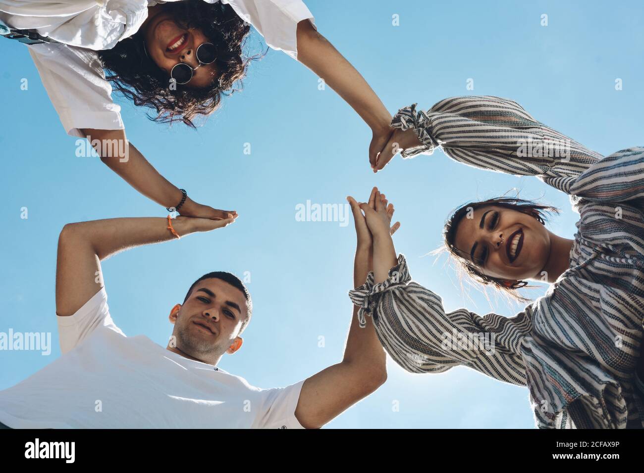 Group of friends embraced and putting their hands together. All of them ...