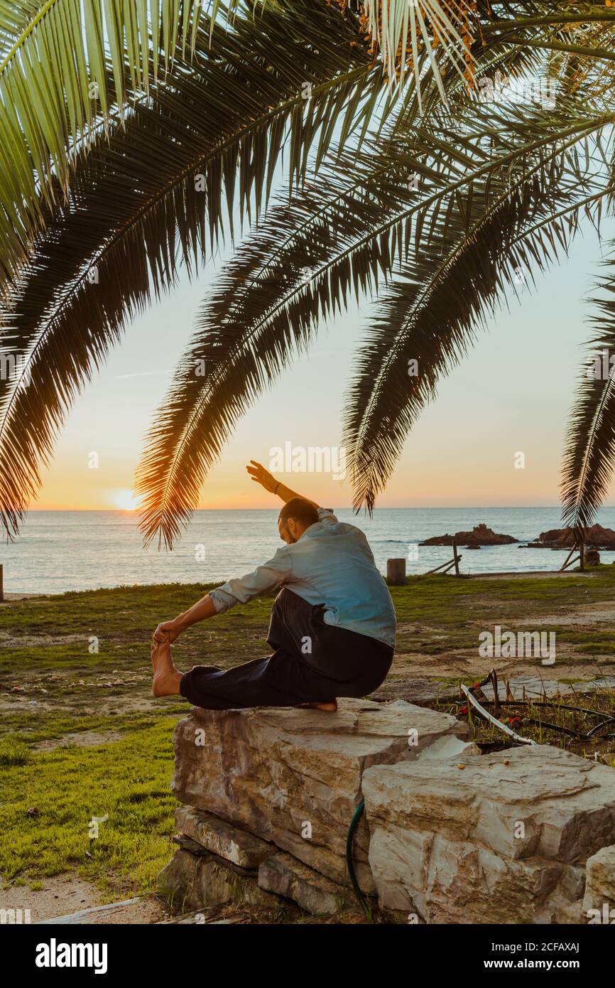Back view of man in active wear crossing legs with one leg extended and ...