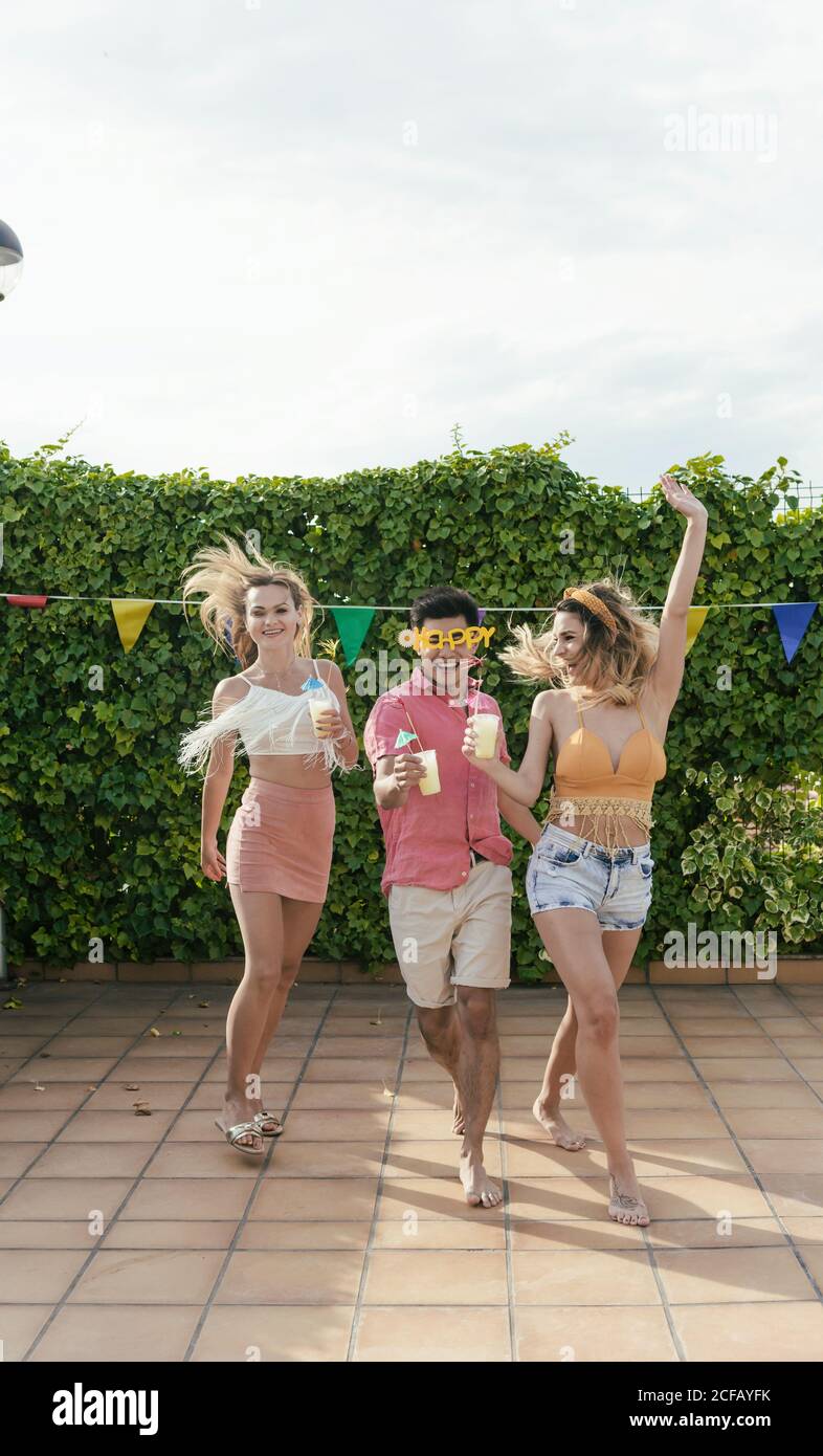 Group of friends having a pool party while they dance, laugh and drink ...