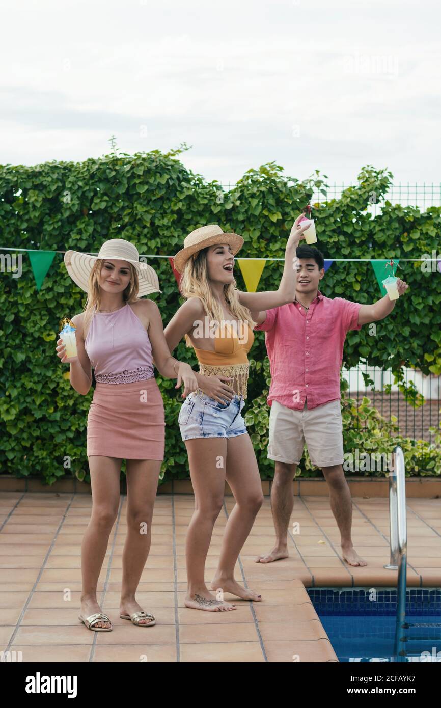 Group of friends having a pool party while they dance, laugh and drink ...