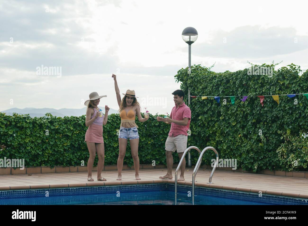 Group of friends having a pool party while they dance, laugh and drink ...