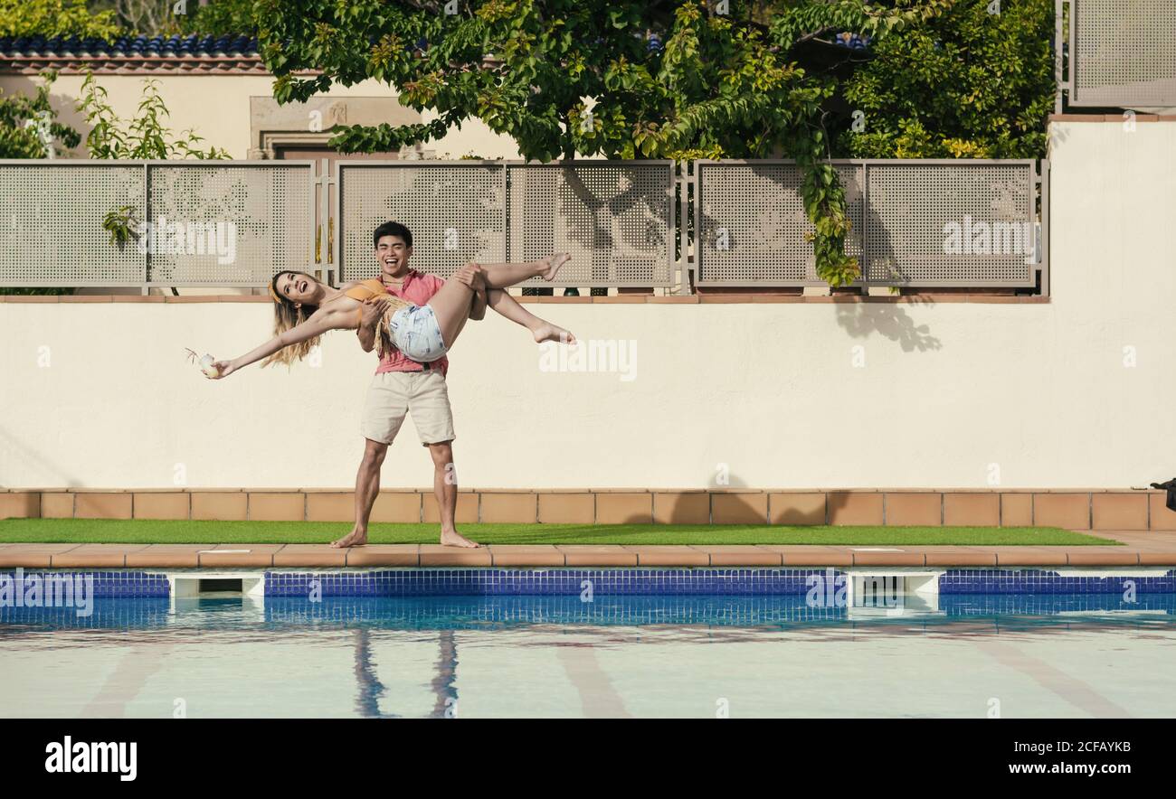 Group of friends having a pool party while they dance, laugh and drink ...