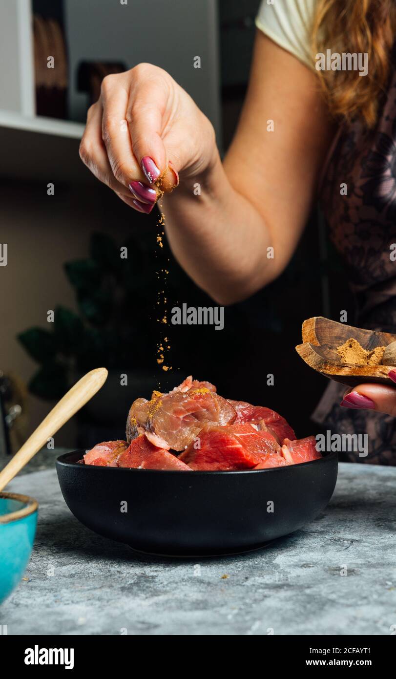faceless Woman wearing apron standing at table and adding salt into ...
