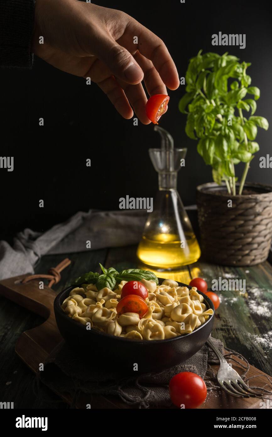 Man adding tomatoes to bowl with ravioli Stock Photo - Alamy