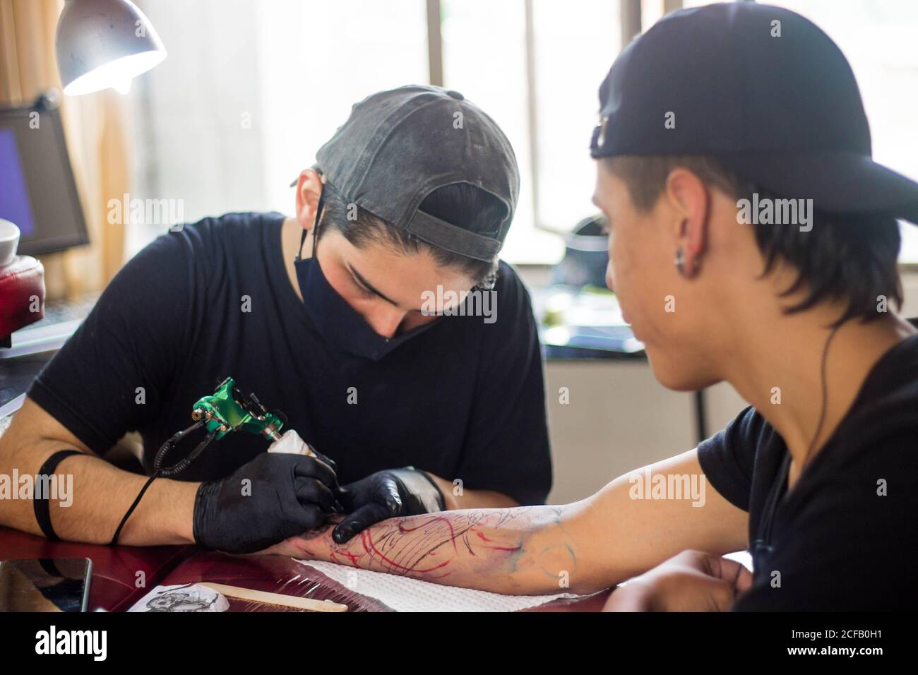 Closeup of a young male tattoo artist with gloves and a facemask giving ...