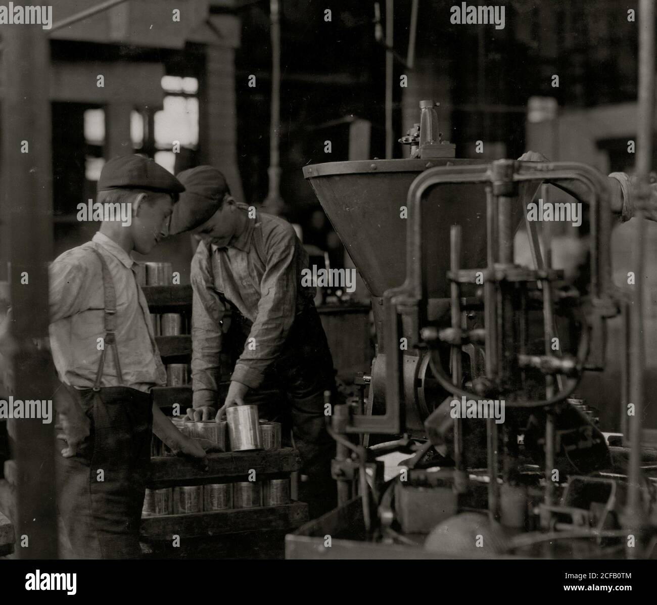 A canning machine and some of the boys] Small boys work at and around ...