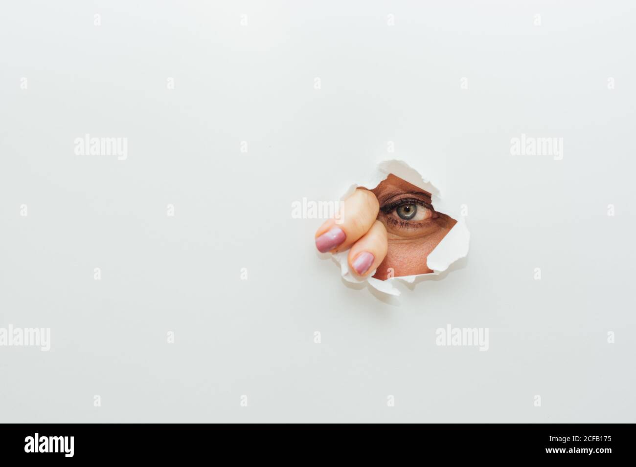 Blue eye of unrecognizable female using fingers to looking away through ...