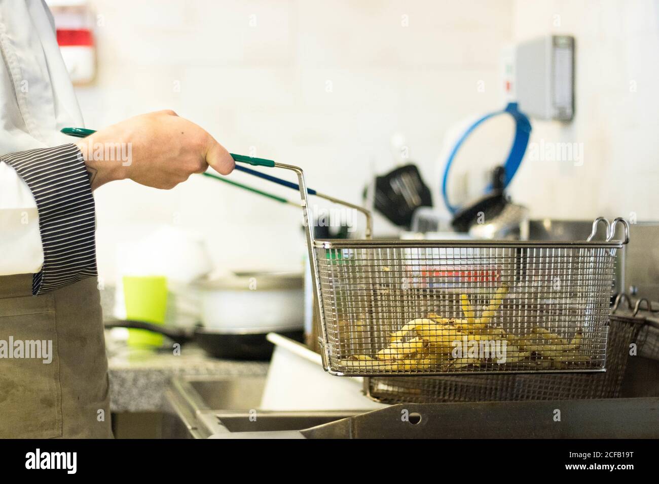 Cook preparing french fries in the kitchen Stock Photo - Alamy