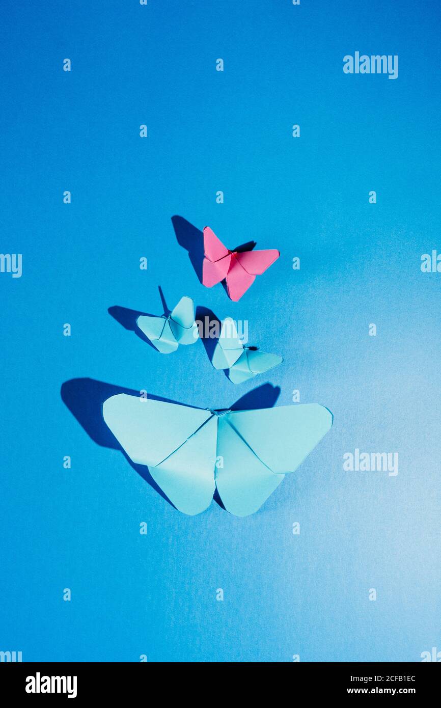 Fragile butterflies made of paper and attached to blue silk fabric ...