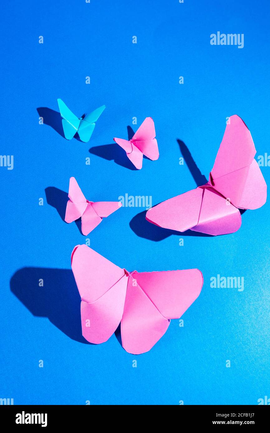 Fragile butterflies made of paper and attached to blue silk fabric ...