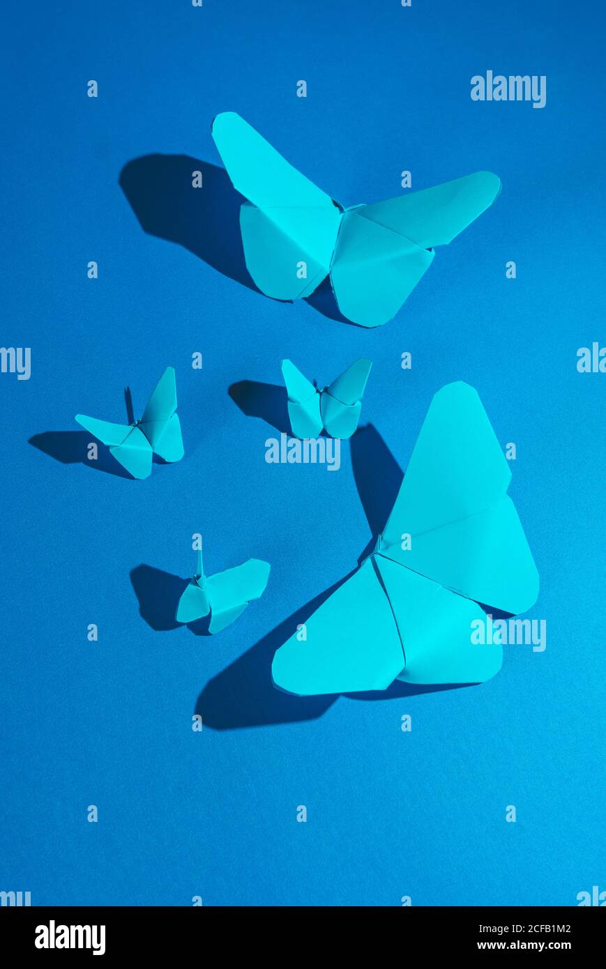 Fragile blue butterflies made of paper and attached to blue silk fabric ...