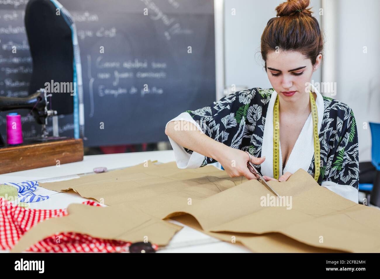 Teenage girl student practicing sewing on modern machine in cozy ...