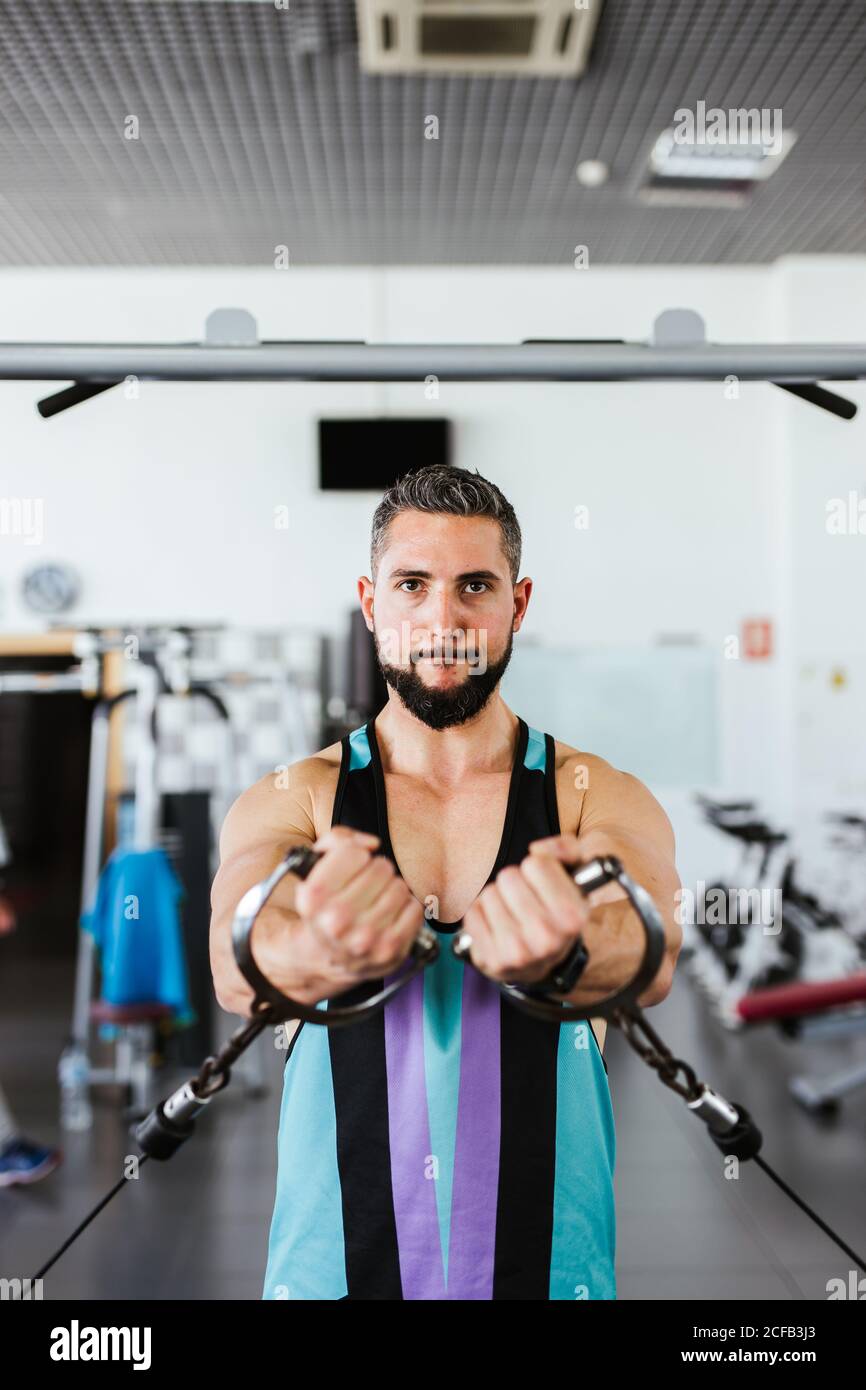 Powerful male bodybuilder in sportswear performing exercise with cable ...