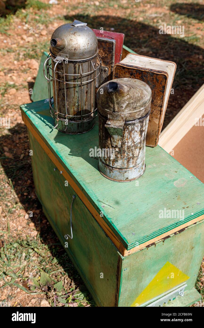 From above of old metal bee smokers placed on green wooden beehive box ...