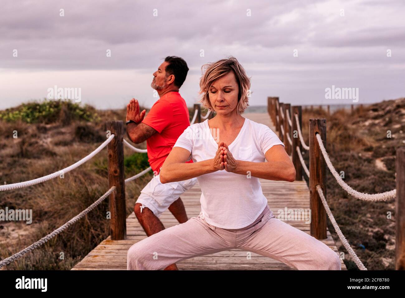 Adult couple meditating on wooden path Stock Photo - Alamy