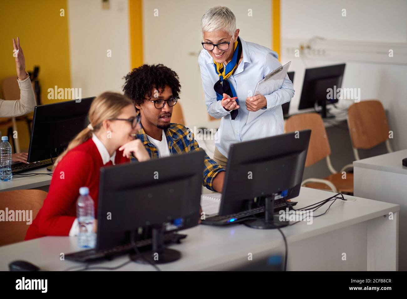 Female teacher in classrom looking in computer of pupils Stock Photo ...