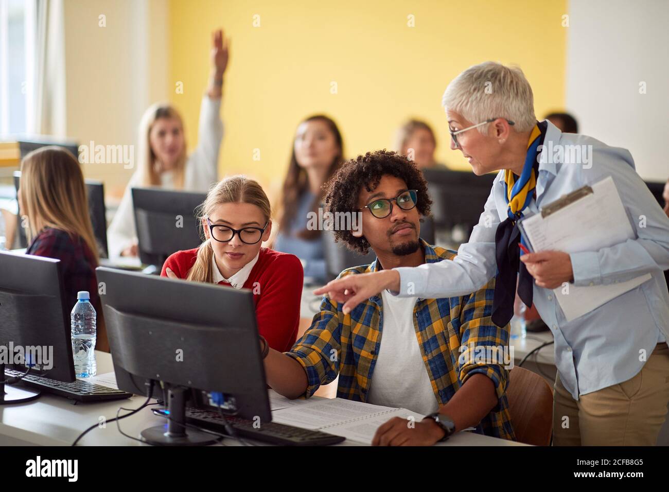Female professor showing to pupils task on computer Stock Photo - Alamy