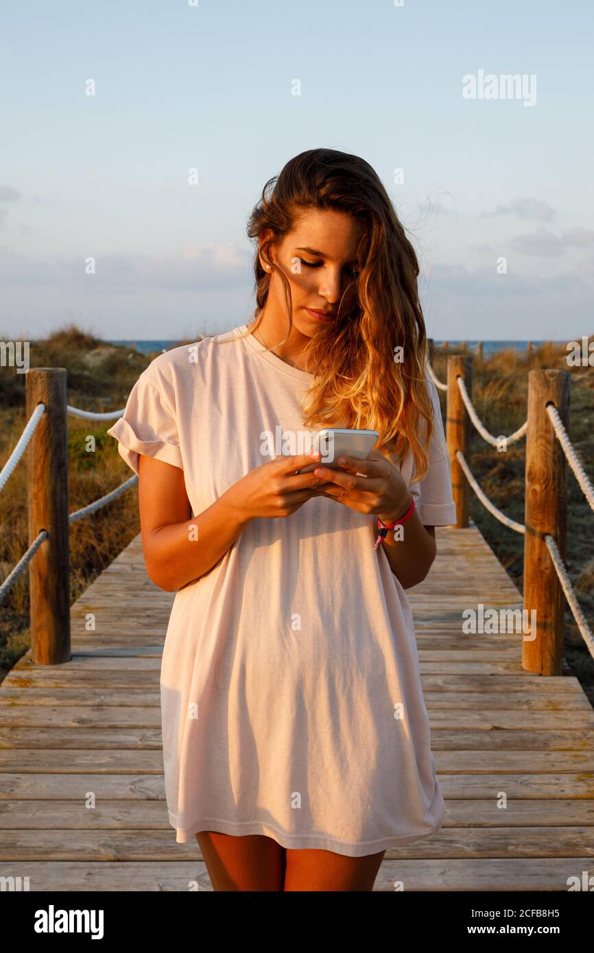 Pensive long haired Woman surfing mobile phone while walking on ...